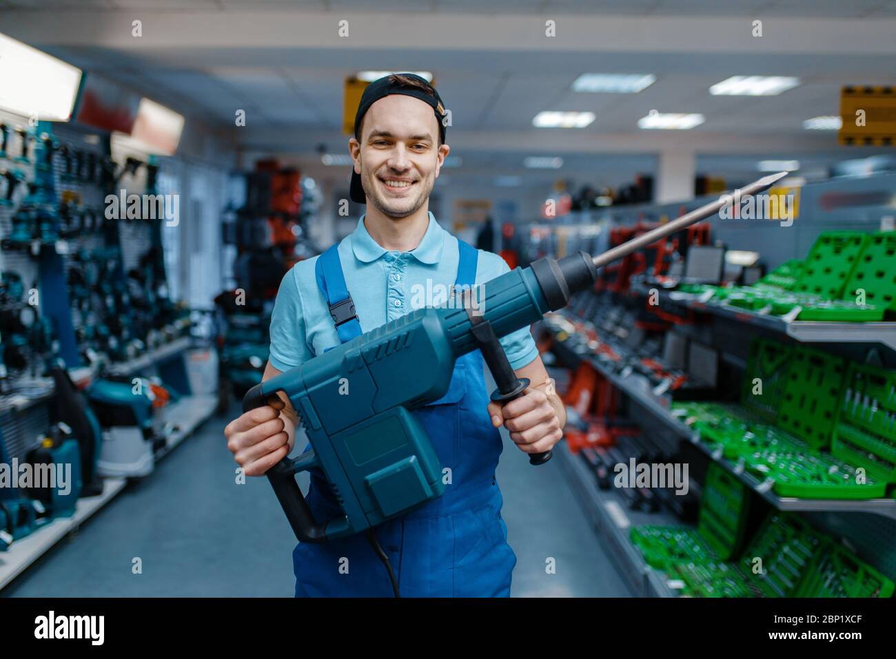 Worker holds big electric perforator in tool store Stock Photo - Alamy