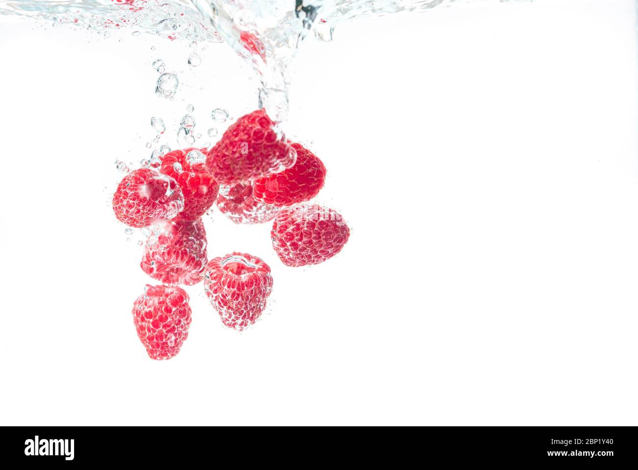 Raspberries splashing into crystal clear water with air bubbles Stock ...