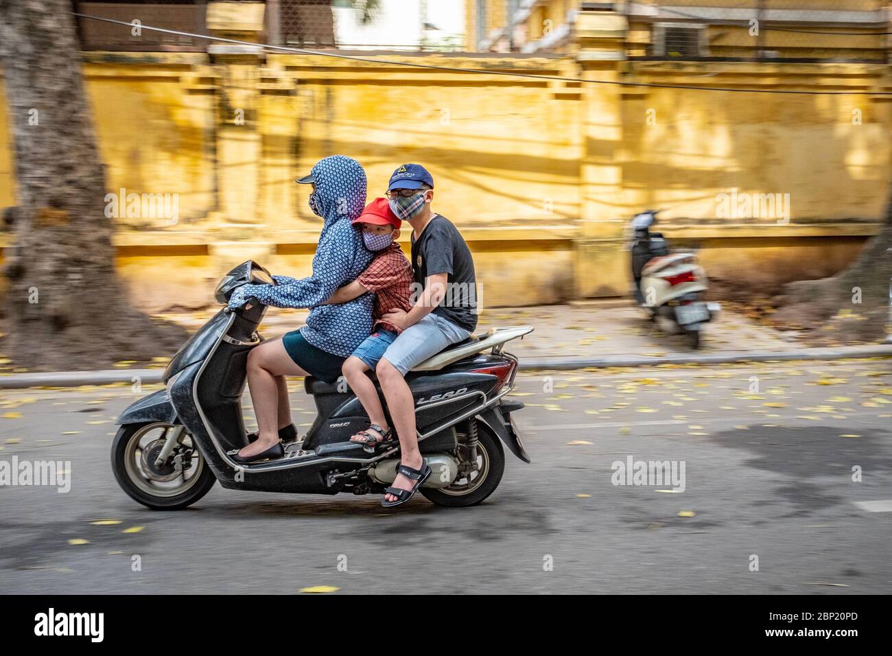 Hanoi, Vietnam - May 1, 2018: A mum with 2 kids on a motorcycle wearing ...