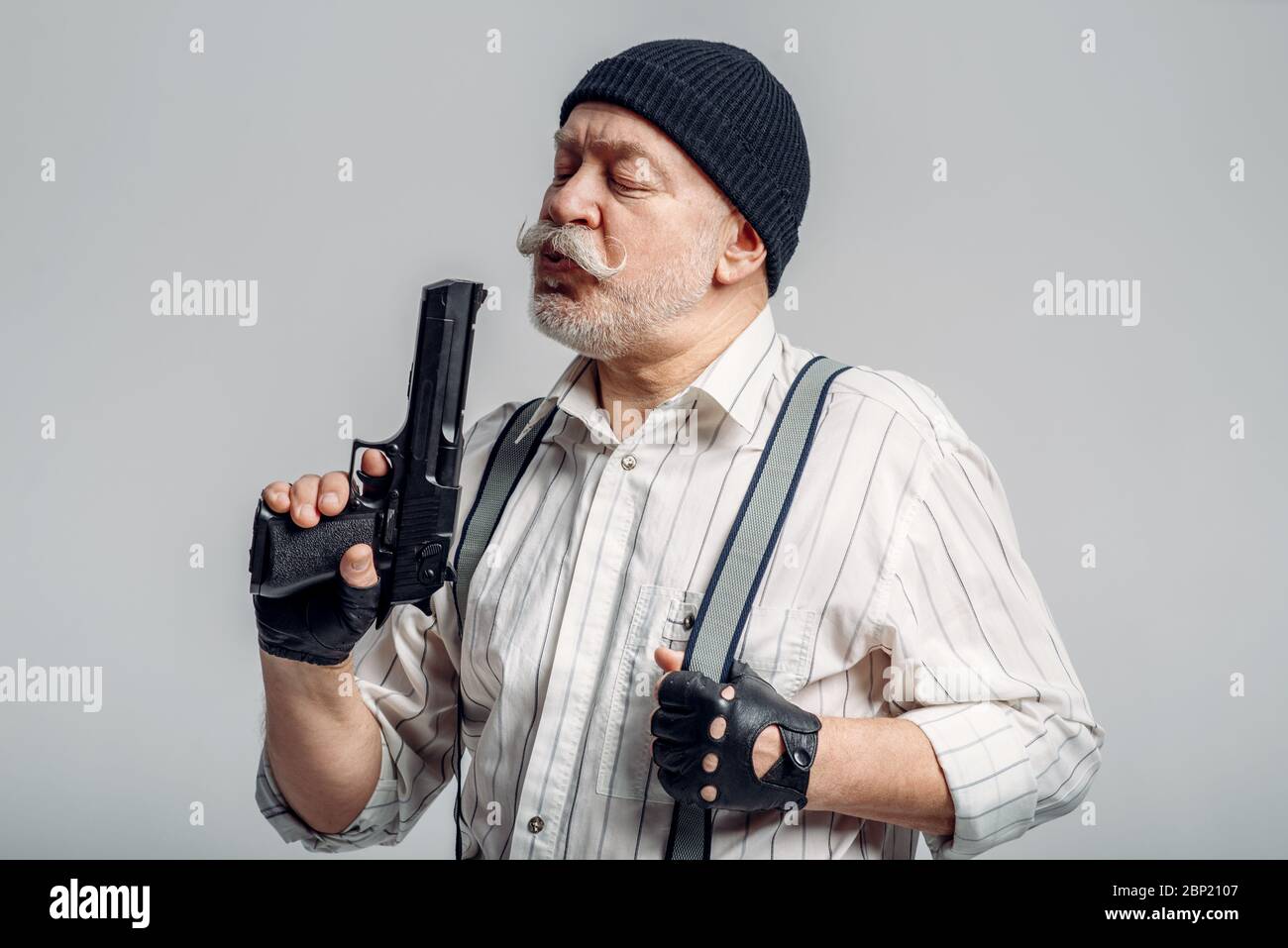 Elderly man with gun isolated on grey background Stock Photo - Alamy