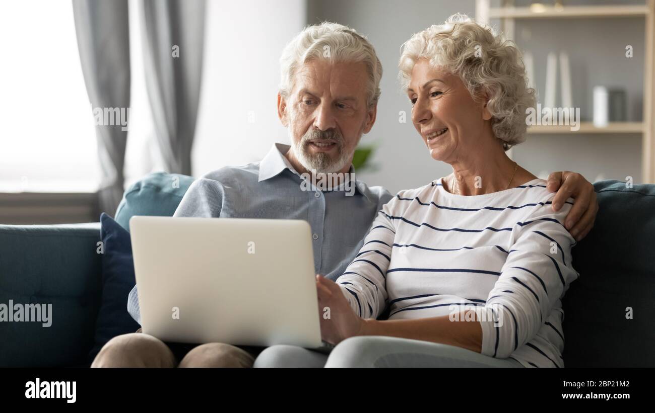 Happy middle aged family couple relaxing on sofa, using computer Stock ...