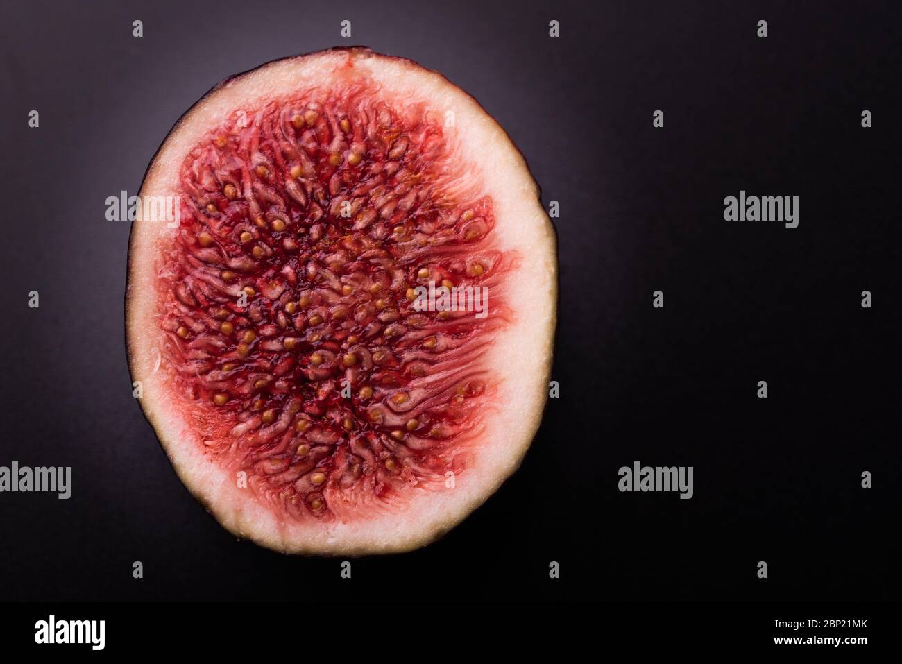 Cut in half fresh fig isolated on black background. Detailed macro ...