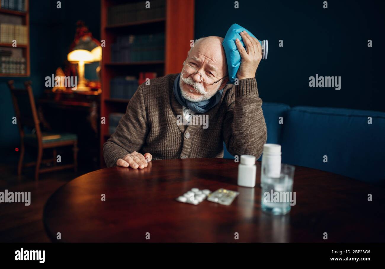 Sick elderly man puts ice on his head, headache Stock Photo - Alamy