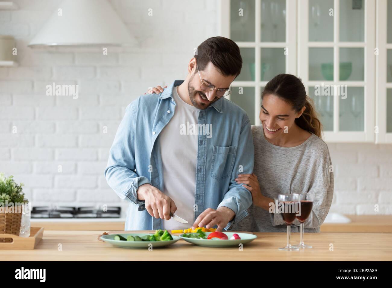 Happy millennial couple cooking food in kitchen together Stock Photo ...