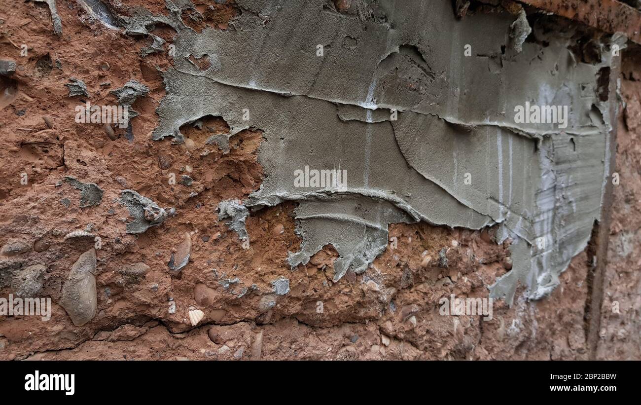 Closeup of rough patch of grey cement on brown textured wall surface ...