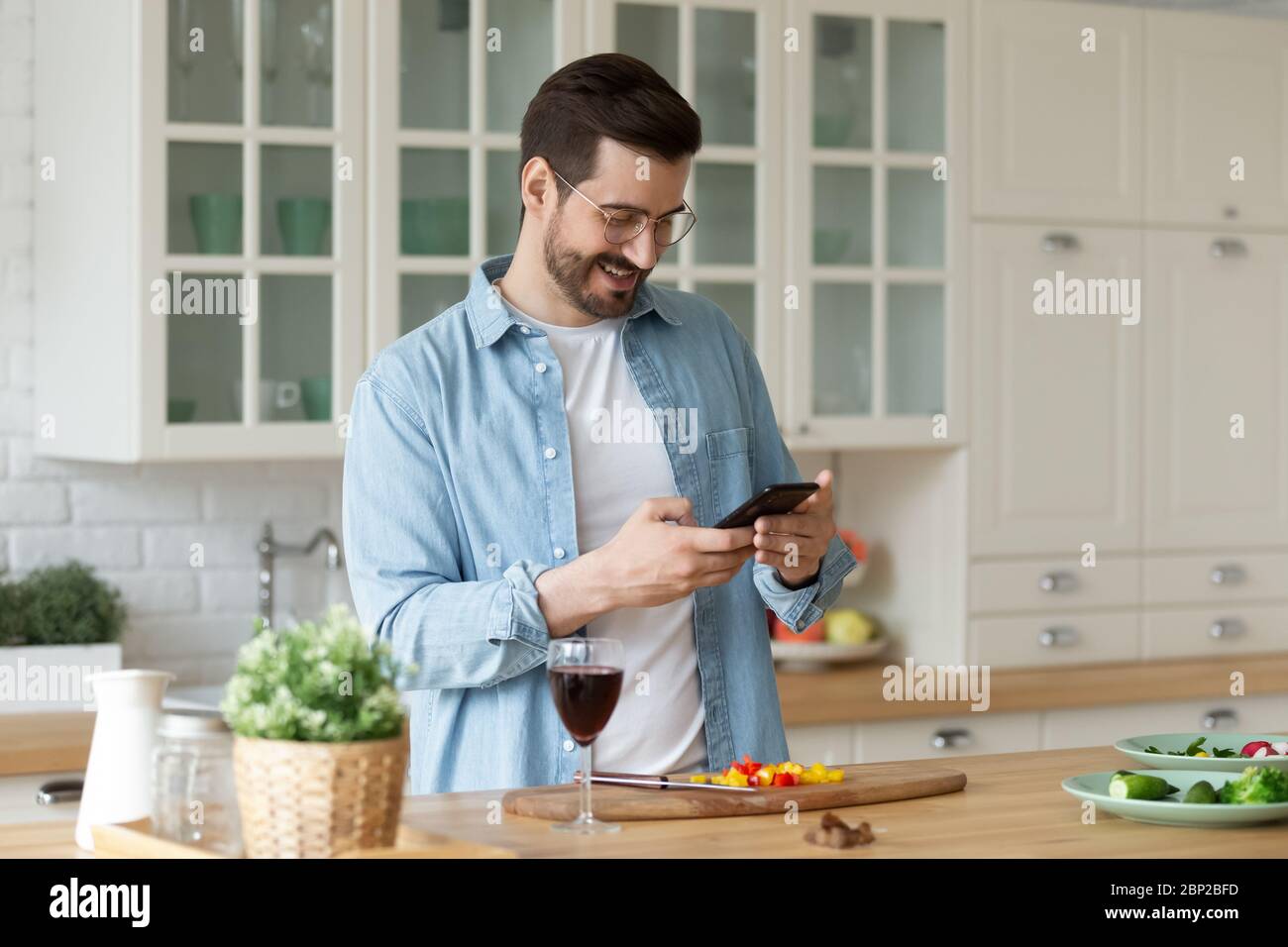 Young man read recipe on cell cooking in kitchen alone Stock Photo - Alamy