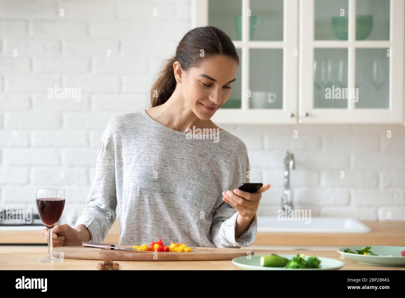 Millennial girl cooking using recipe on cellphone Stock Photo - Alamy