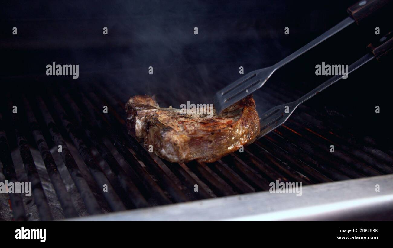 Man turning a piece of grilled meat Stock Photo - Alamy