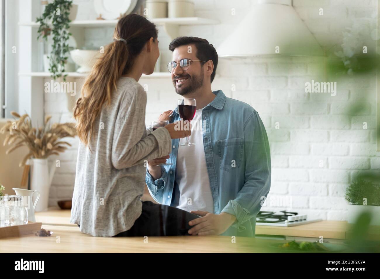 Happy young couple hug drinking wine in home kitchen Stock Photo - Alamy