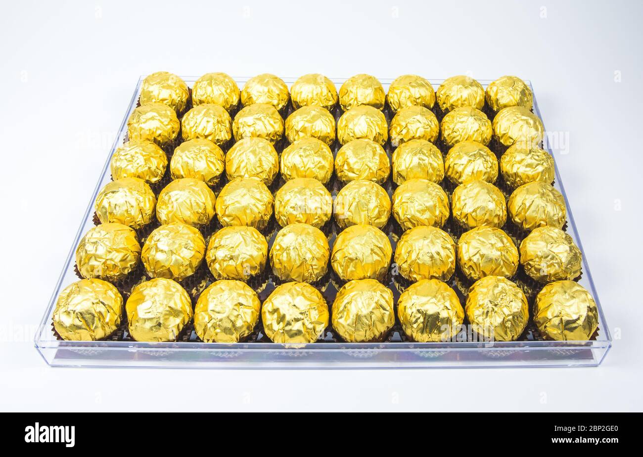 a lot of shiny golden chocolate wrapper in line on white background ...