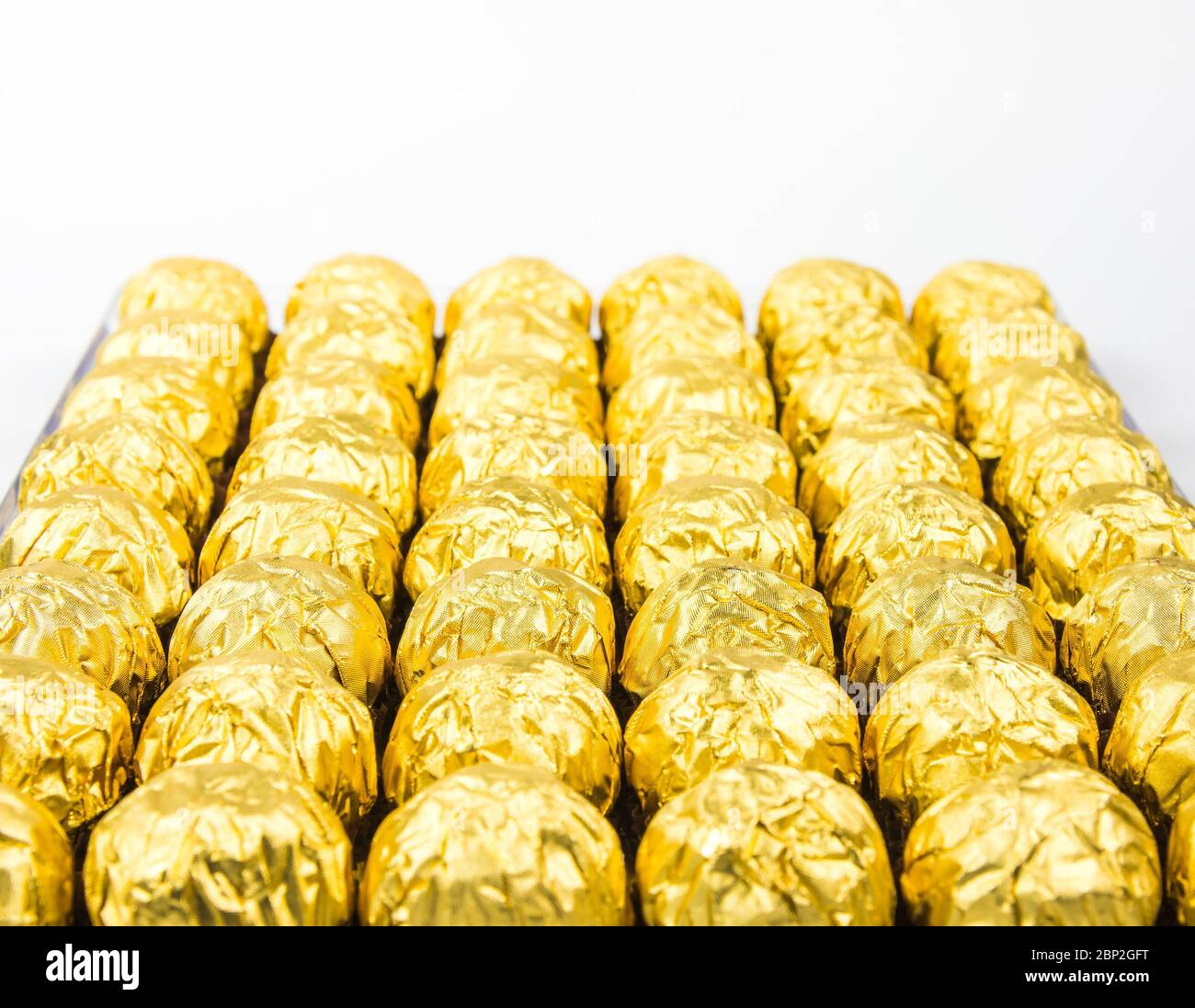 a lot of shiny golden chocolate wrapper in line on white background ...