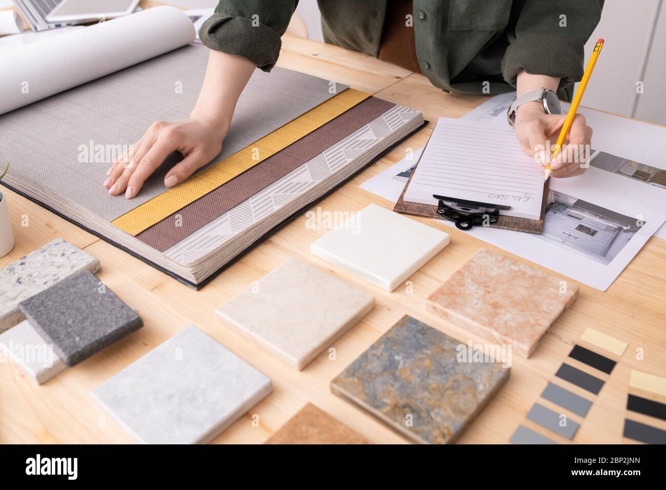 Hands of female interior designer with pencil over paper making notes ...