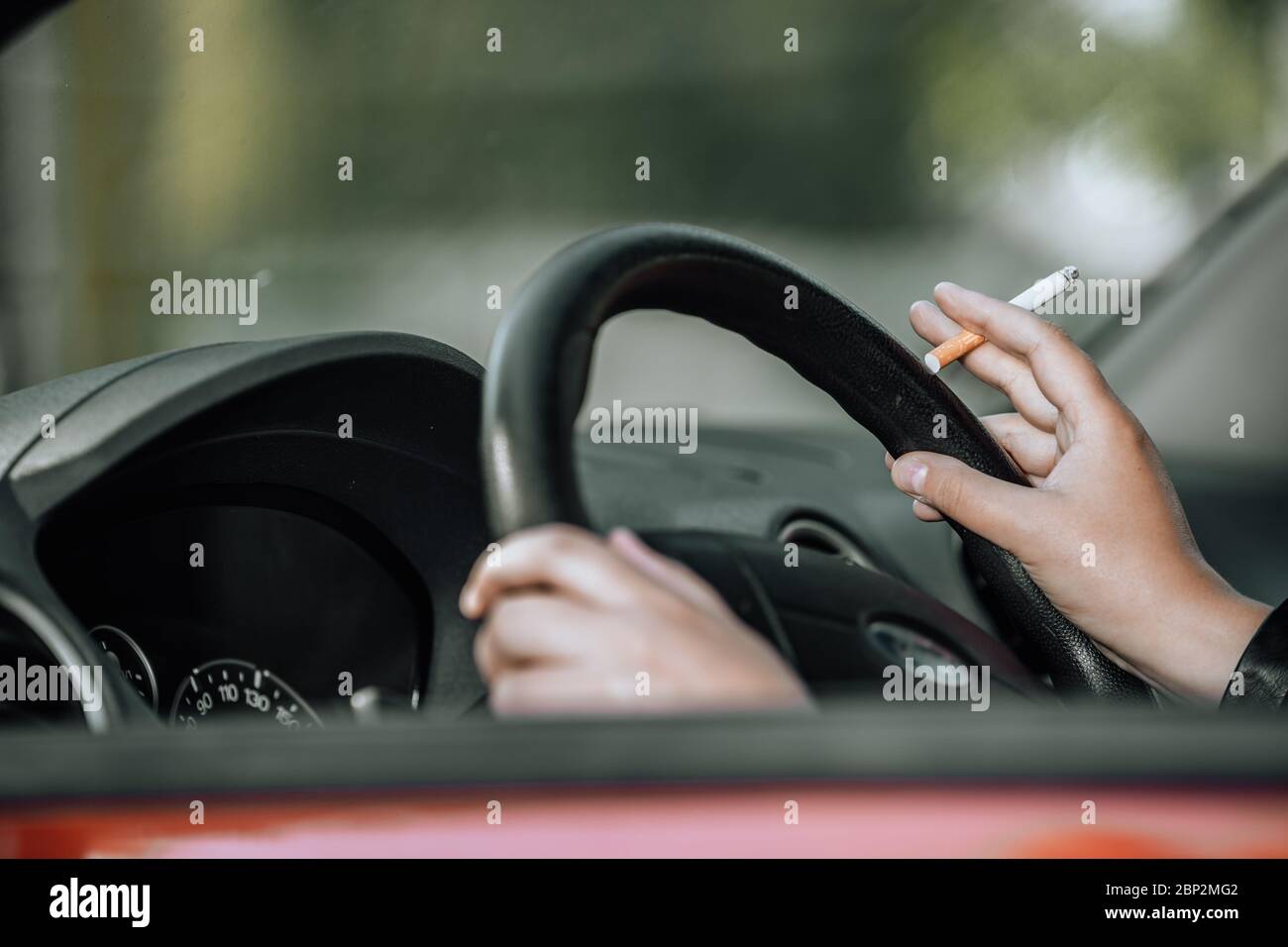 Close up of woman hand smoking cigarette inside the car while driving a ...