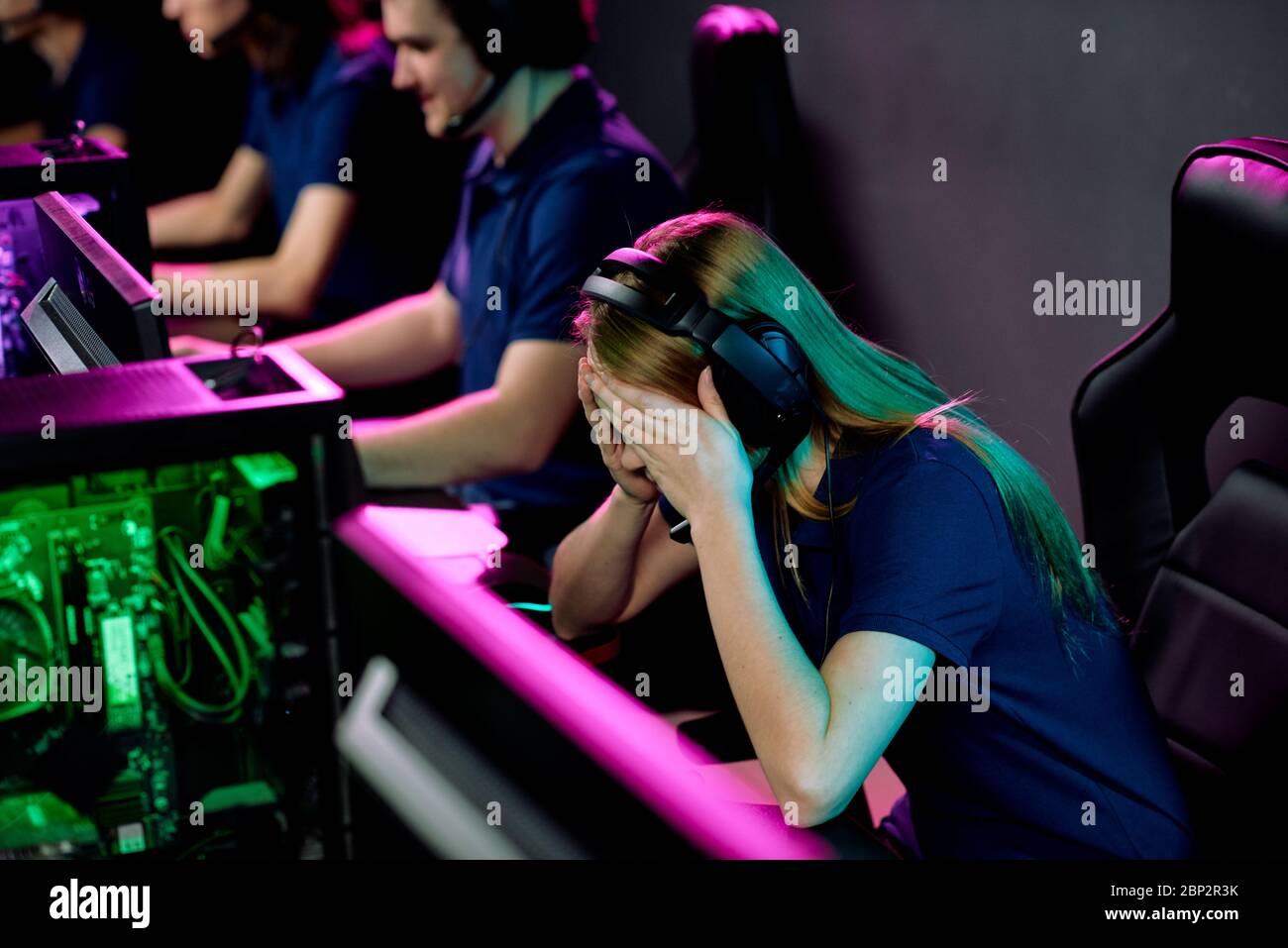 Tired or failed girl in headset touching her head while bending over ...