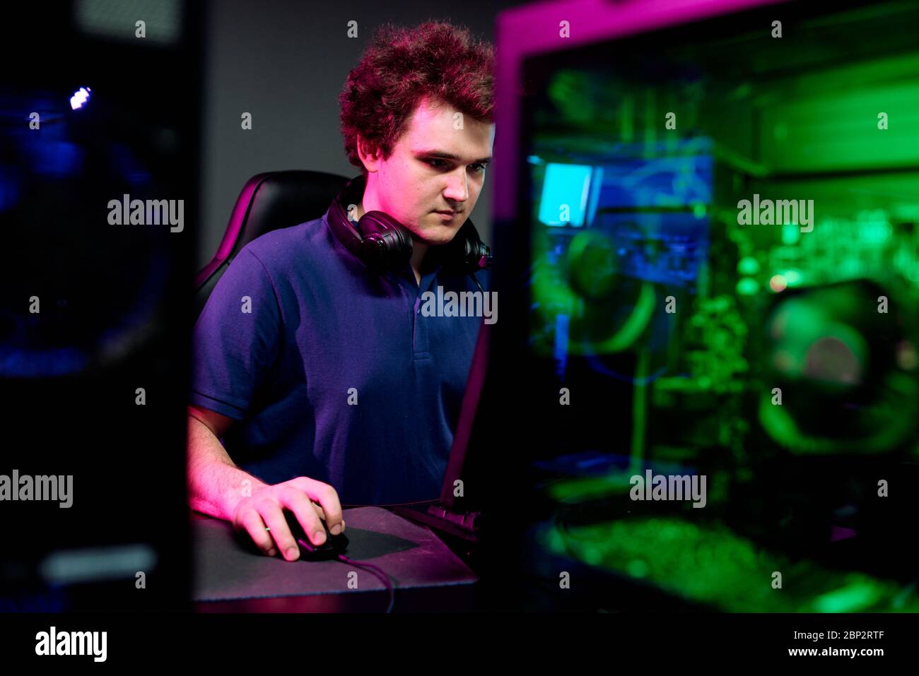 Serious guy with headphones around neck looking at computer screen ...