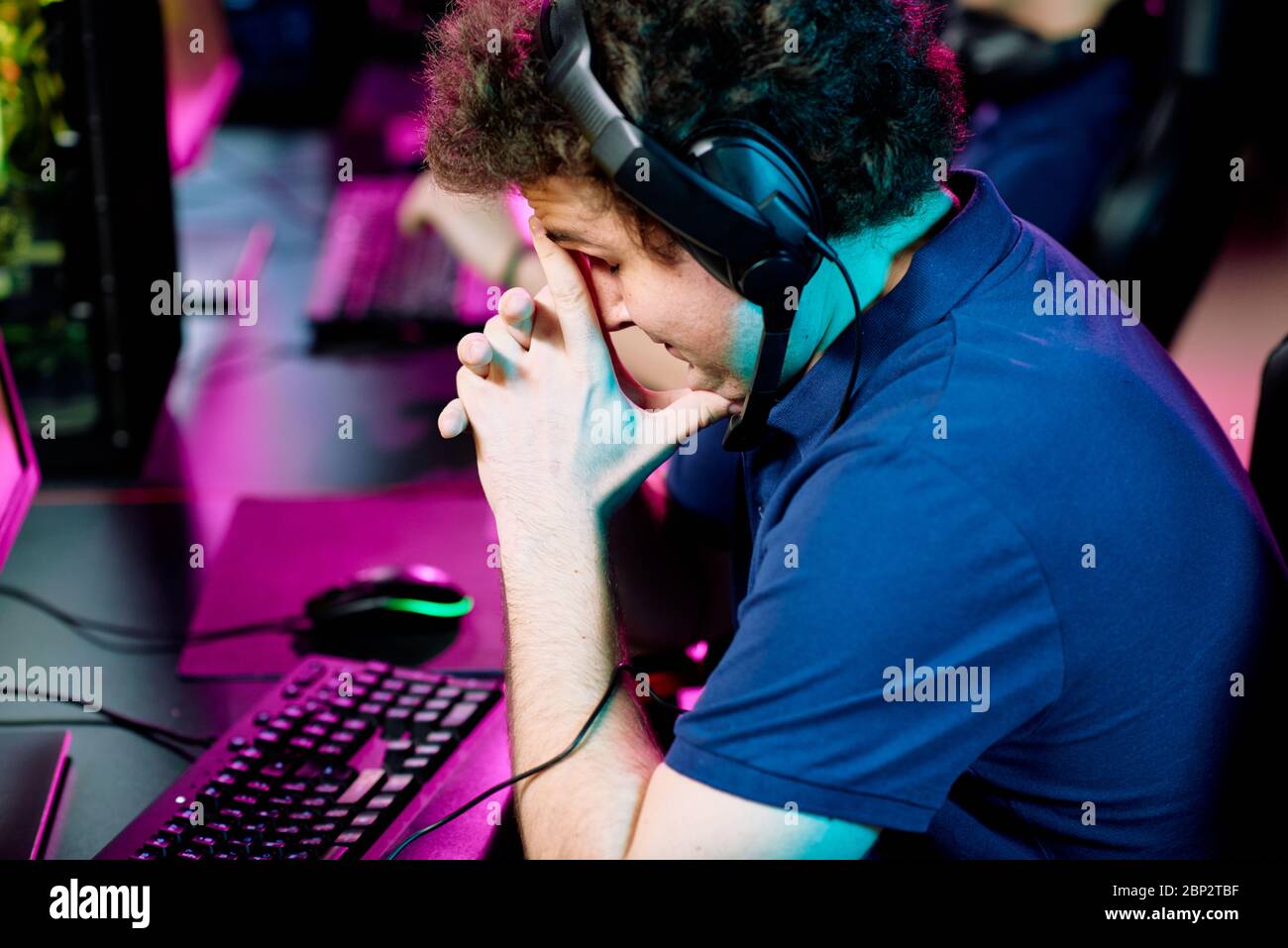 Tense or worried young man in headset touching face while slightly ...