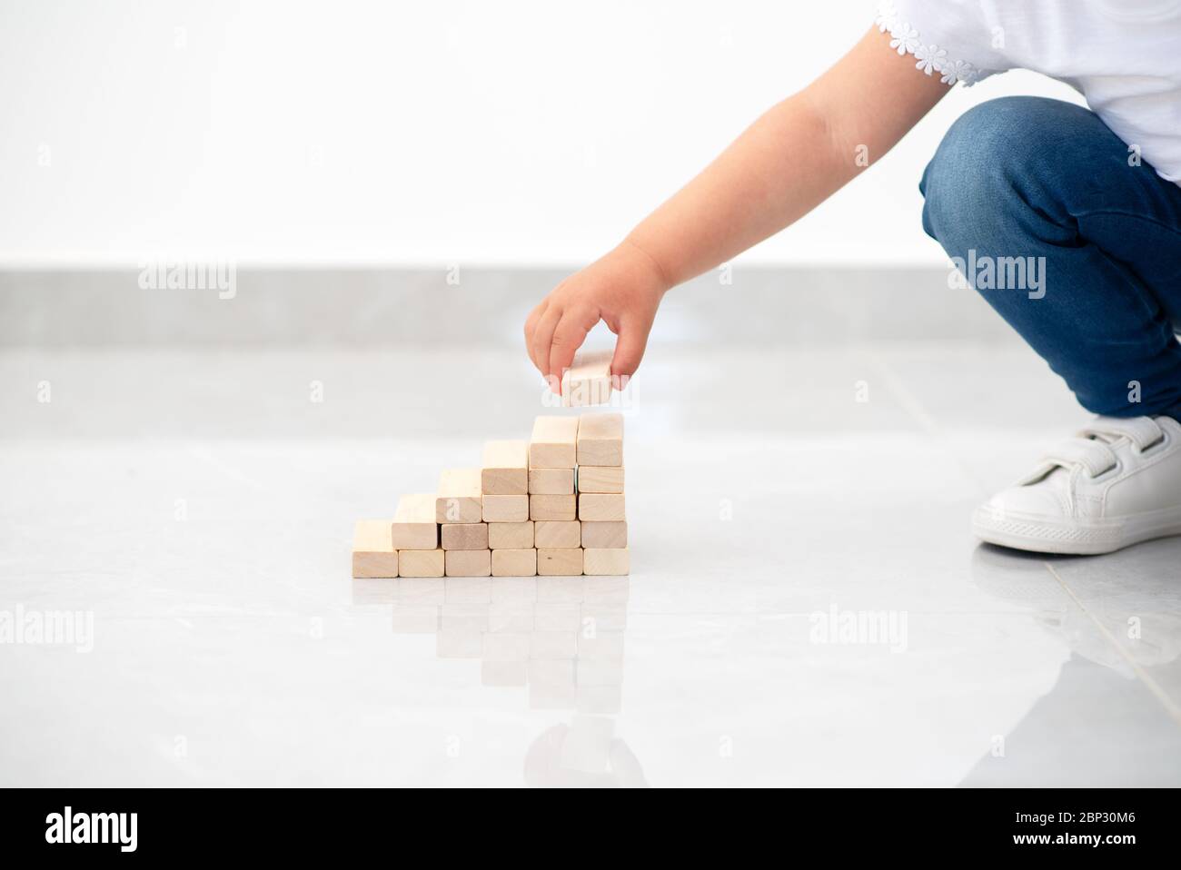 Close up child hand arranging wood block stacking as step stair ...