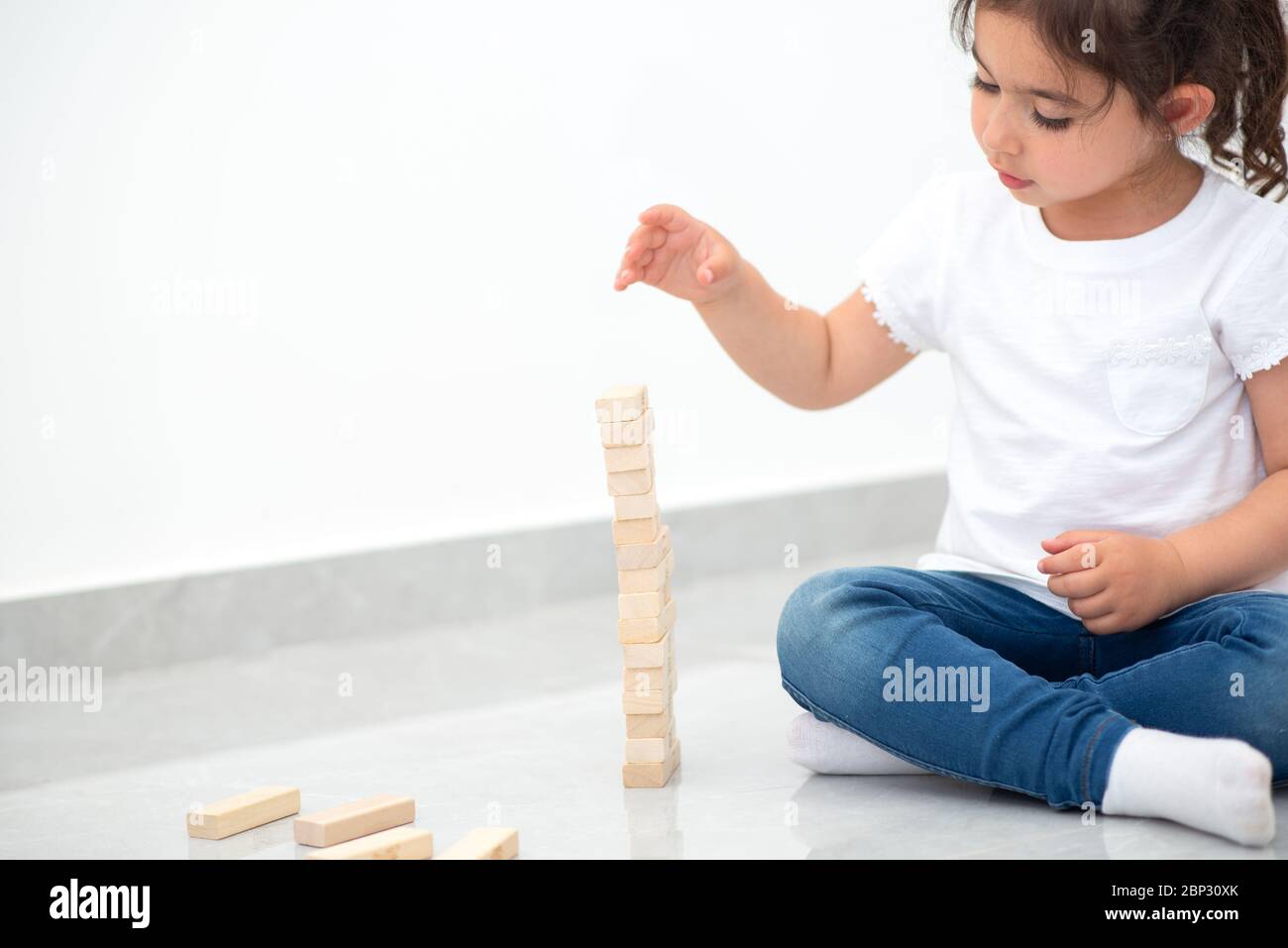 Cute child putting last block to the tower made of wooden blocks ...