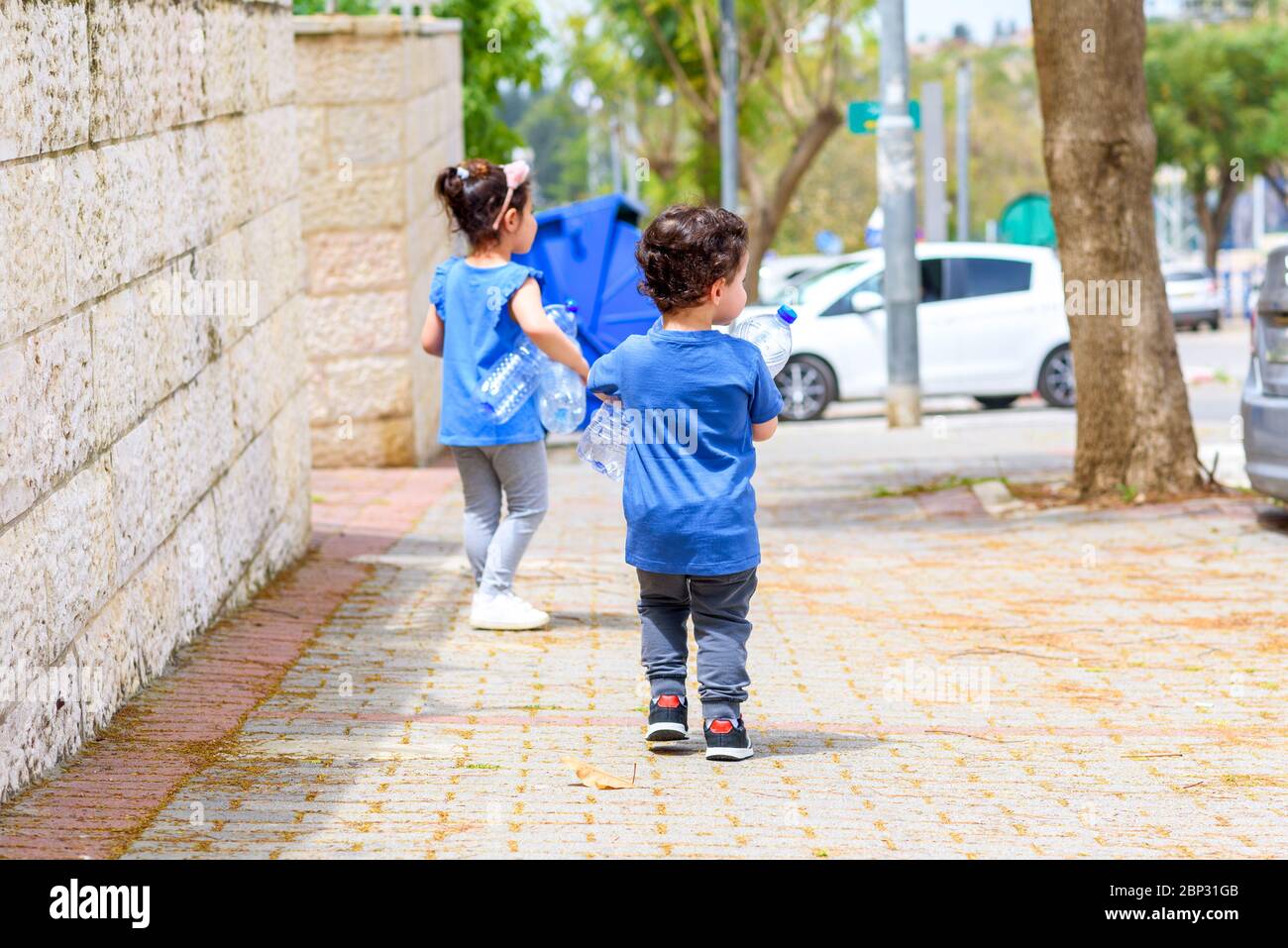 Kids taking out the segregated garbage. Back view little girl and boy ...