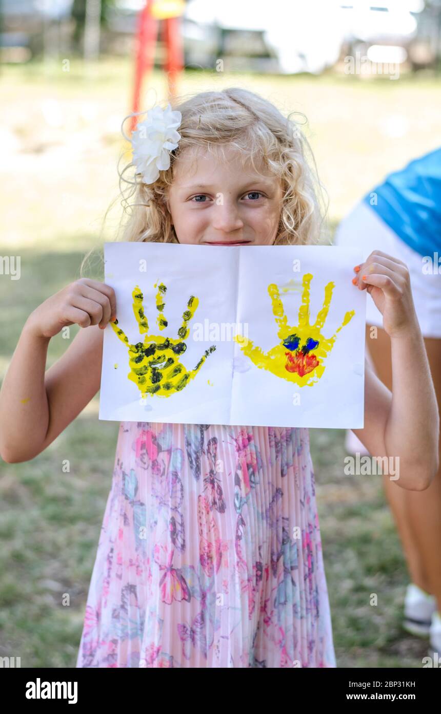 little girl showing hand prints on paper painted with bright colors ...