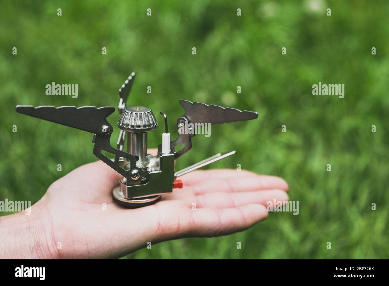 Small tourist burner in the palm of your hand, green grass background ...