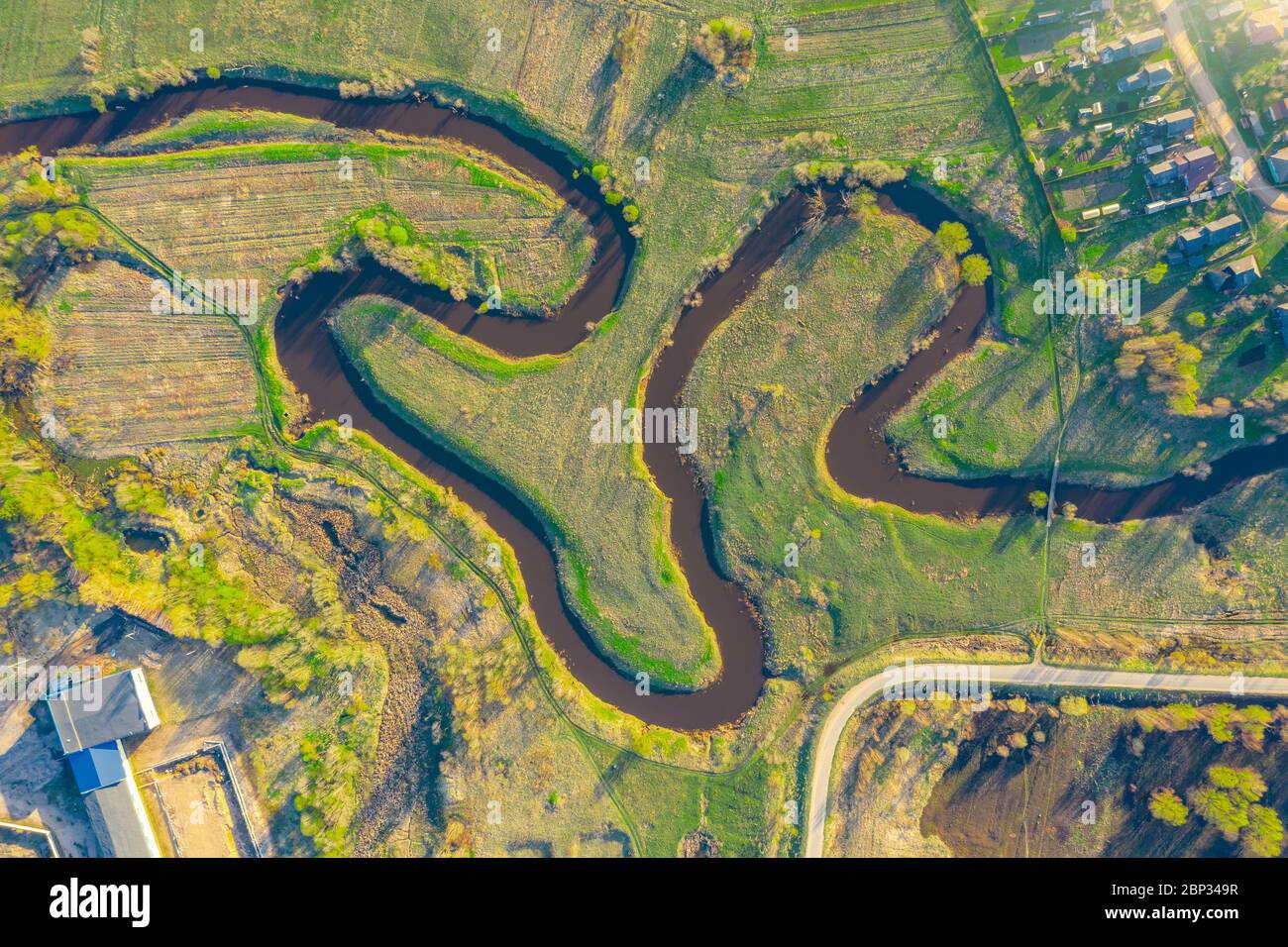 Aerial landscape of winding small river, stream in green field, top ...