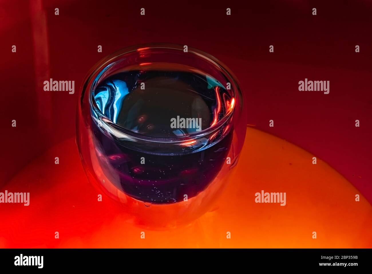 Fashionable double bottom cup with blue liquid on red backround ...