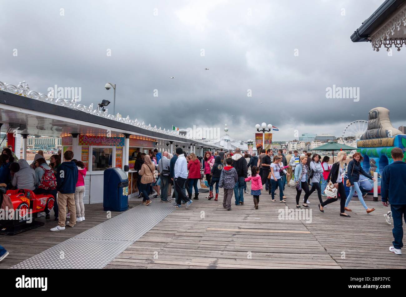 Tourists at Brighton Pier fairground on dull and cloudy summer day in ...