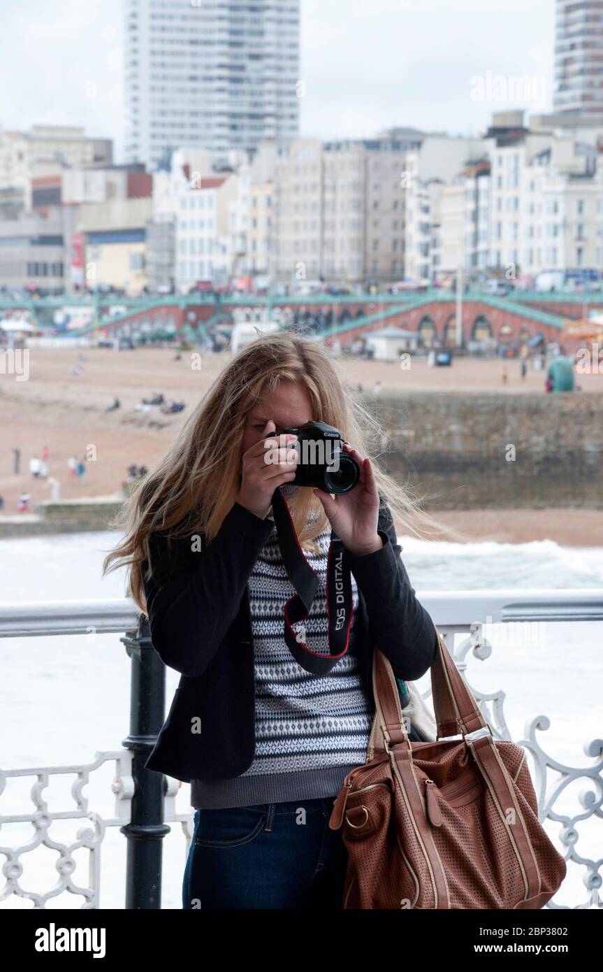 Female tourist taking photos with photo camera at the Brighton Pier ...