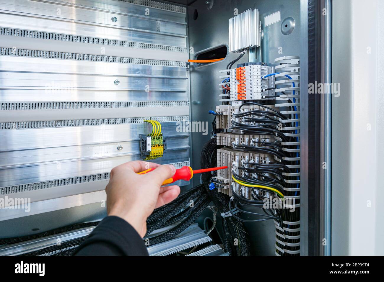 Electrical engineer checking electric cubicle and fixing connector ...