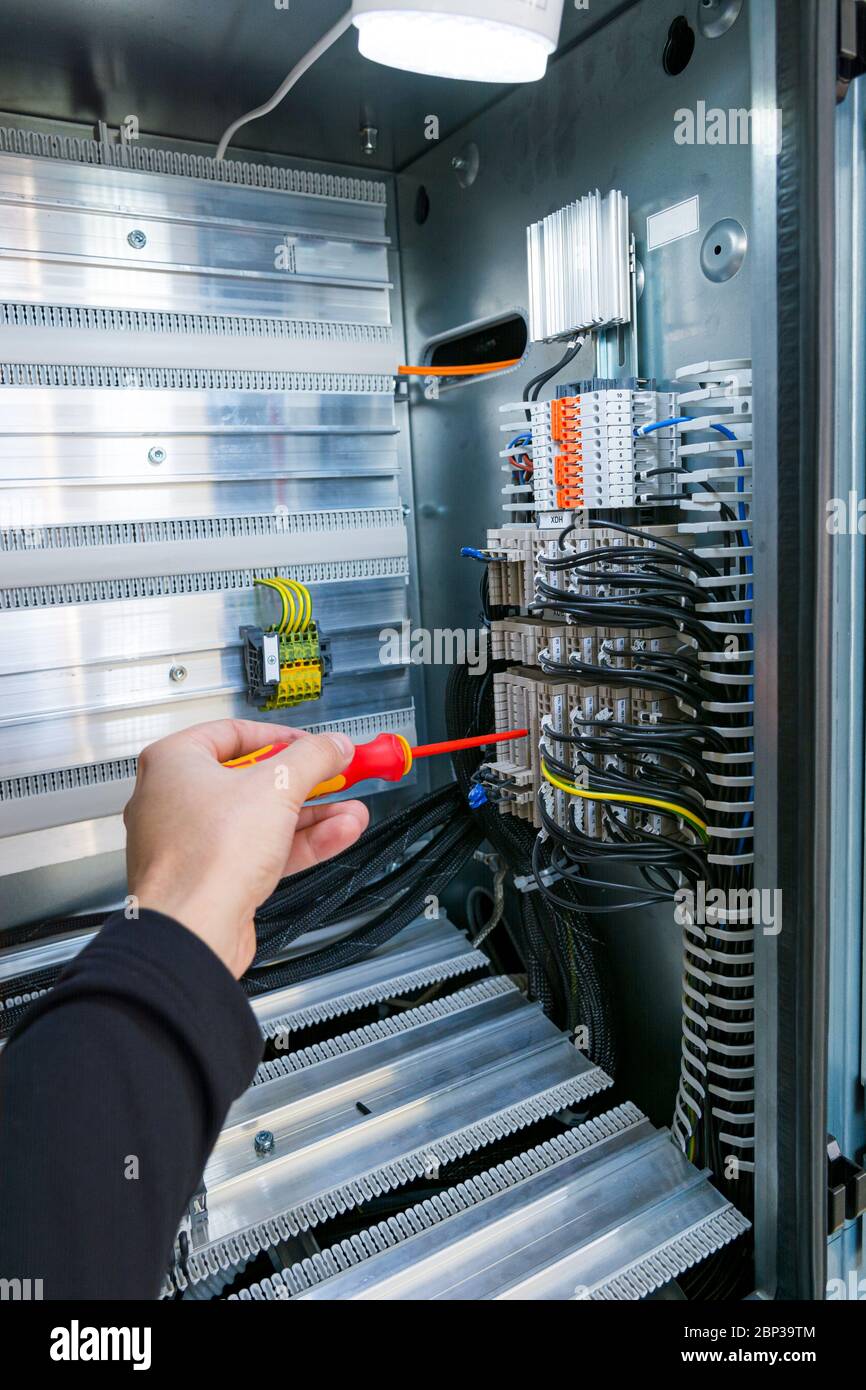 Electrical engineer checking electric cubicle and fixing connector ...