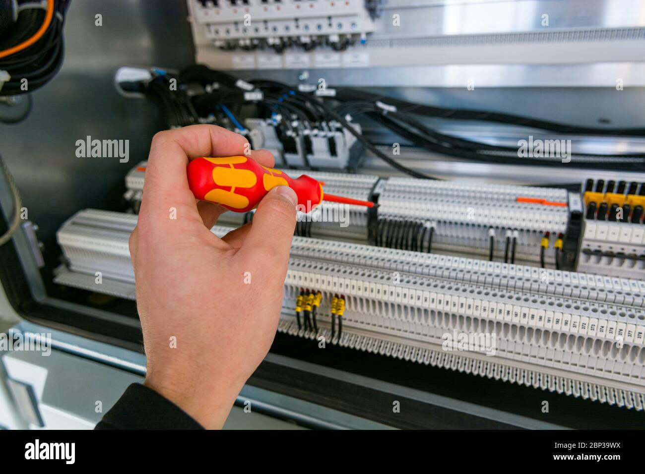 Electrical engineer checking electric cubicle and fixing connector ...