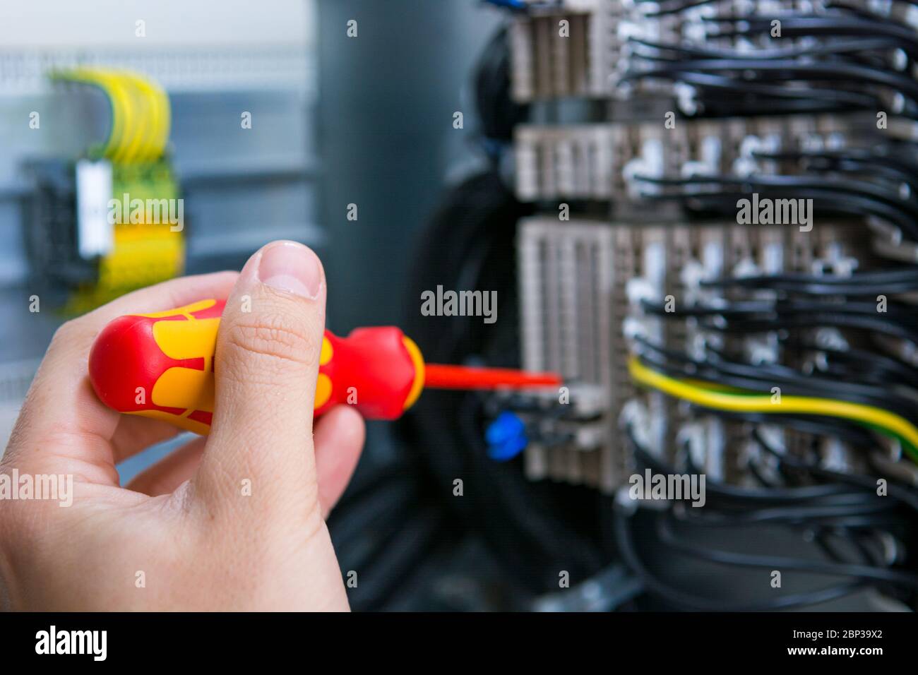 Electrical engineer checking electric cubicle and fixing connector ...
