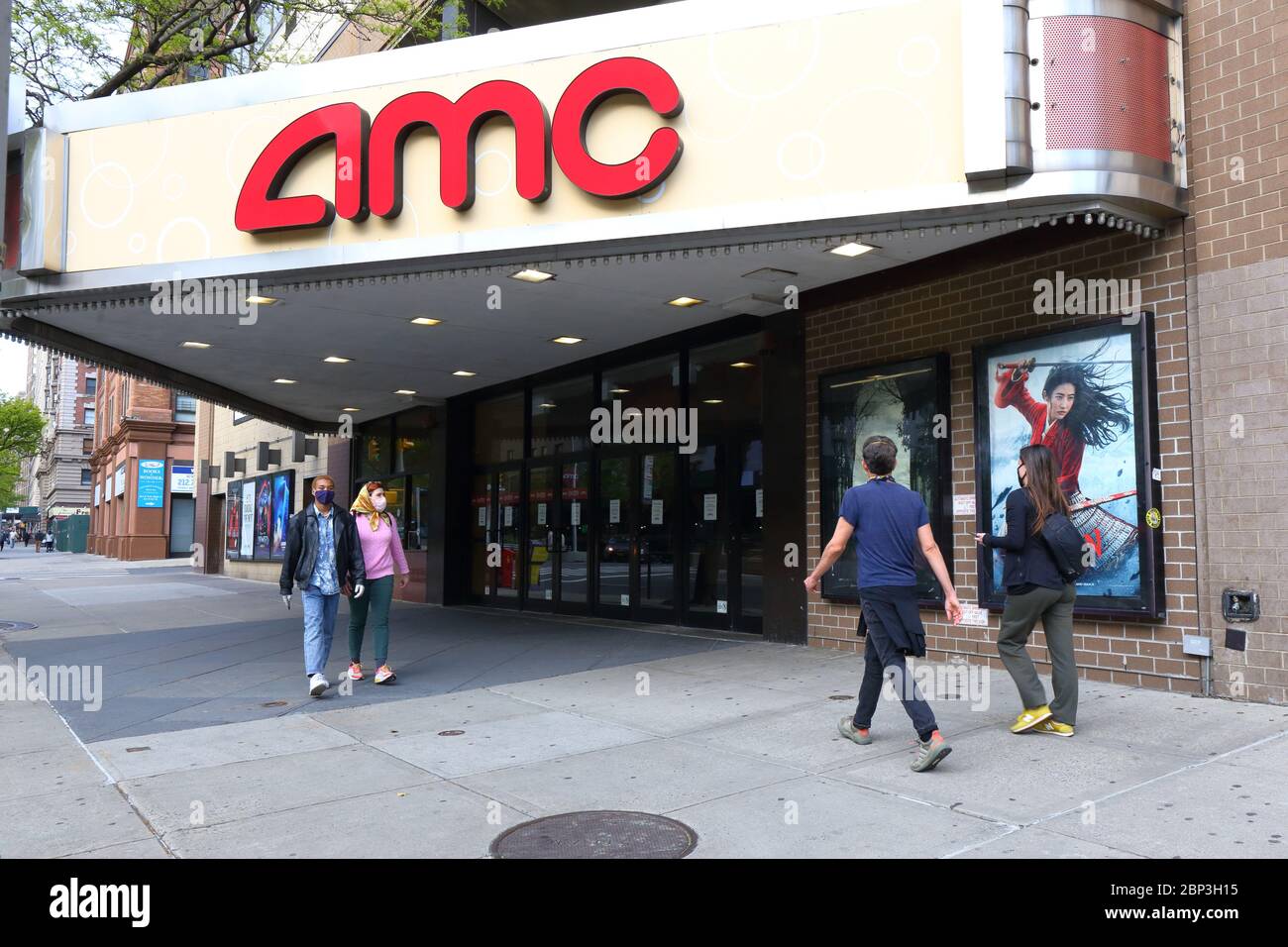 People with face masks walk past a closed AMC theater in the Upper West ...