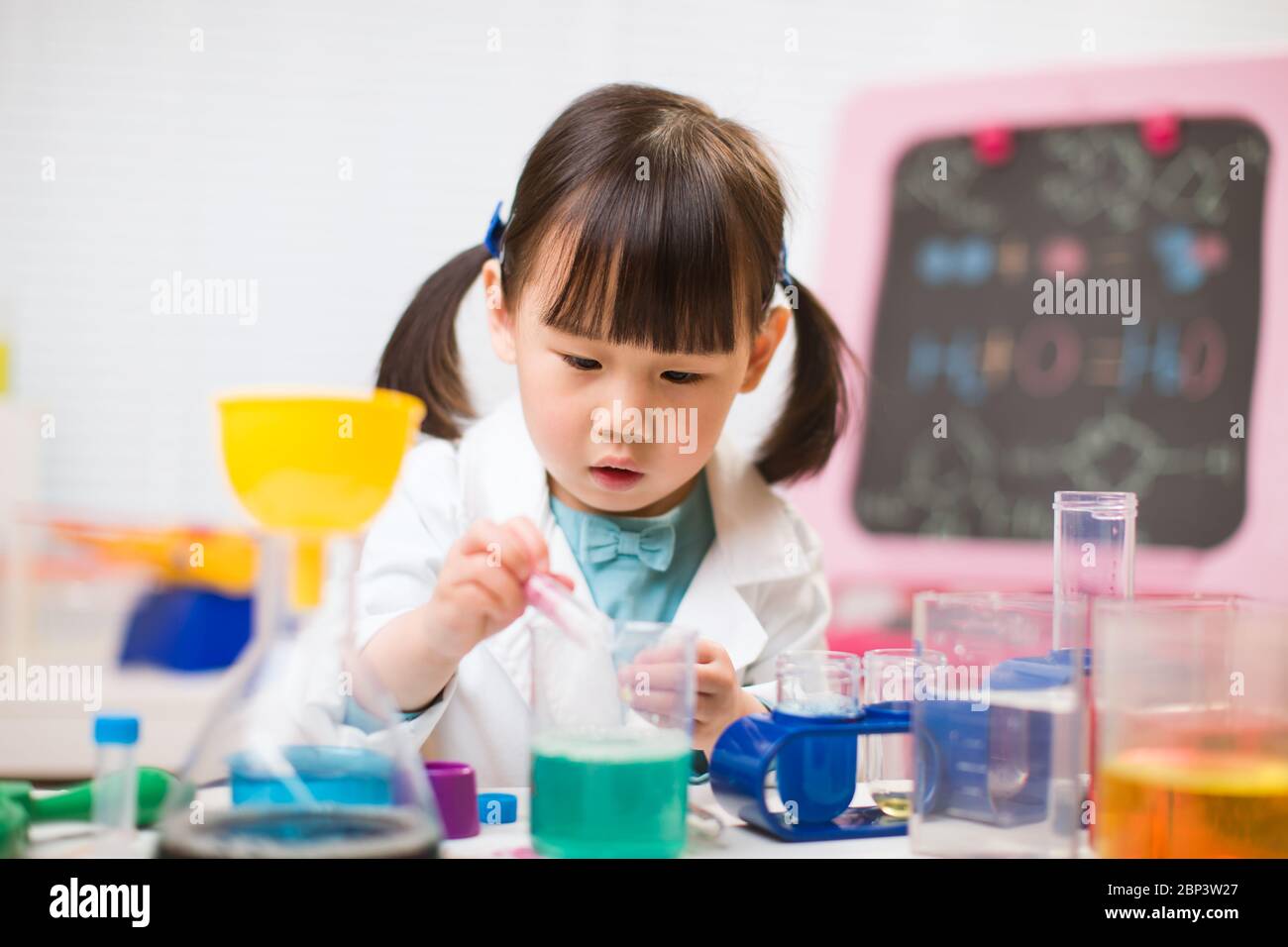 toddler girl pretend play scientist role at home against white ...