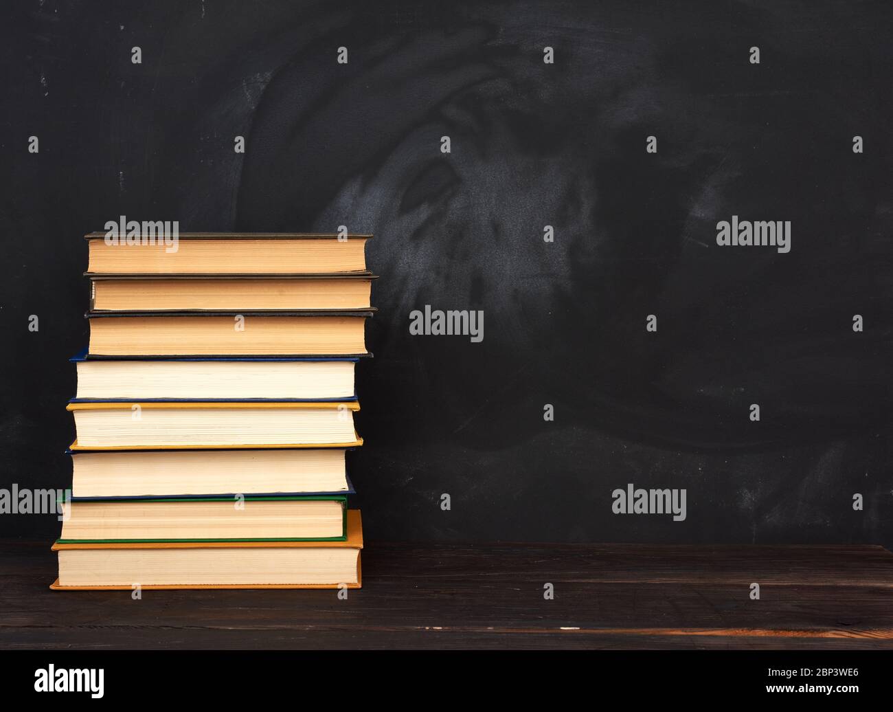 stack of various hardback books on the background of an empty black ...
