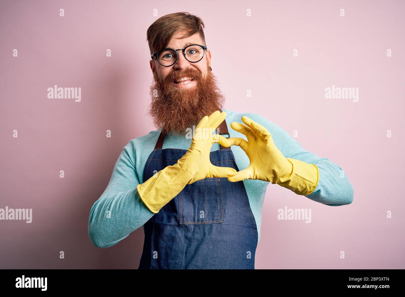 Irish redhead housekeeping man with beard wearing apron and washing ...