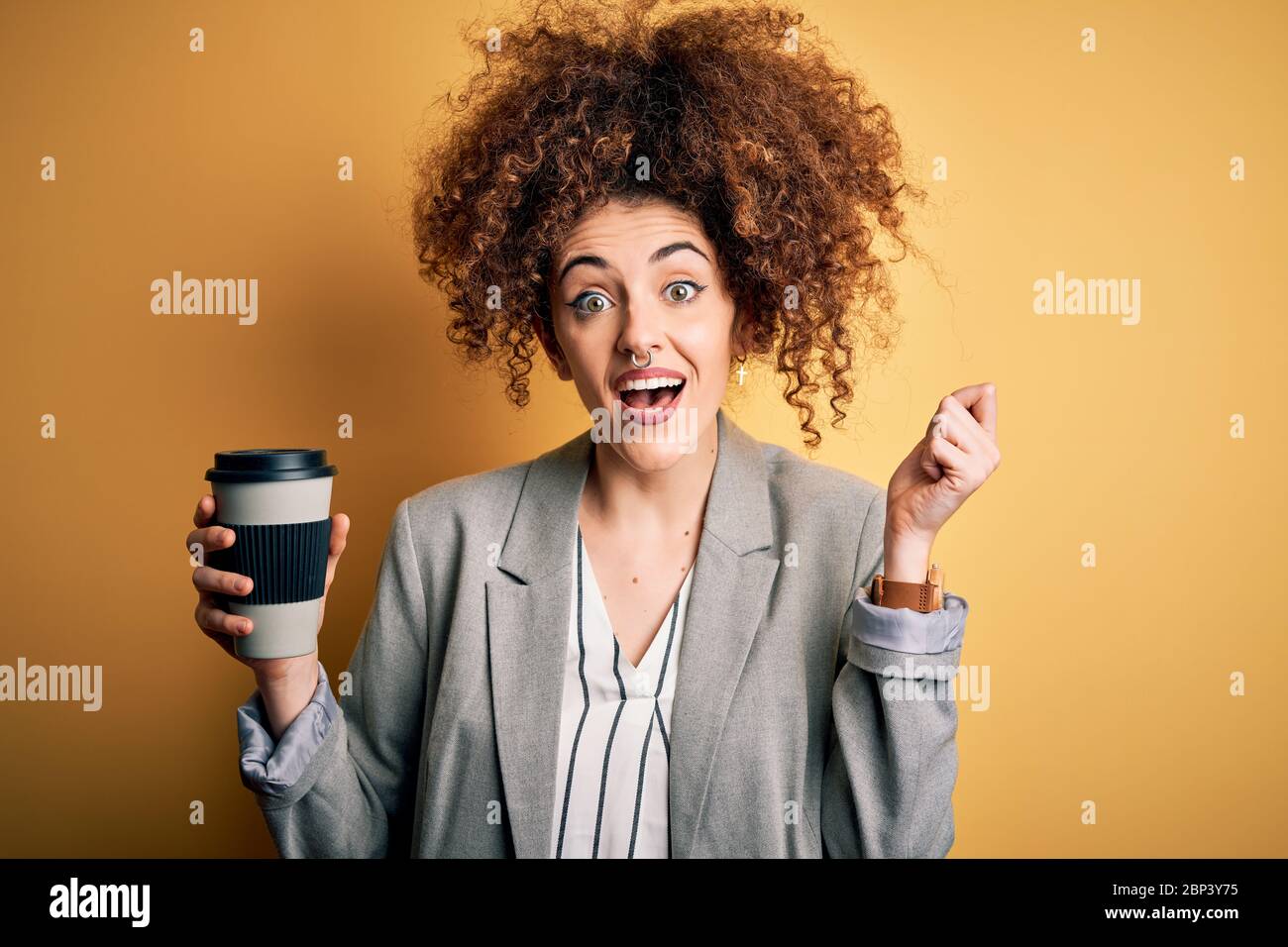 Young beautiful woman with curly hair and piercing drinking glass of ...