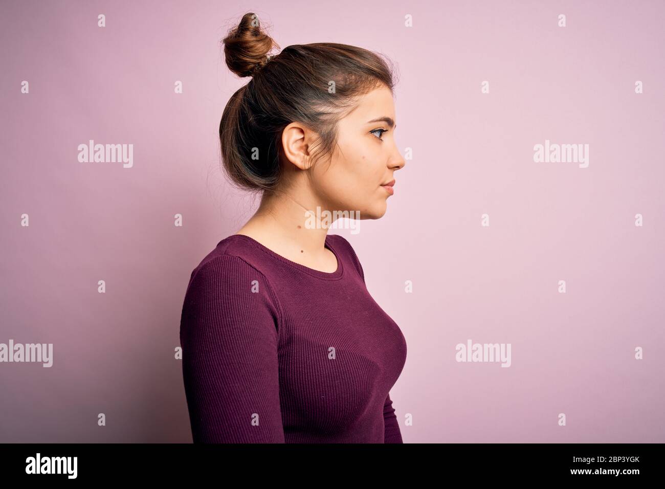Beautiful young woman wearing casual bun hairstyle over pink isolated ...