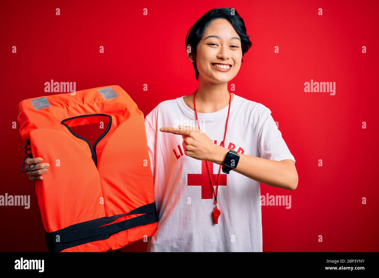 Young beautiful asian lifeguard girl using whistle holding orange life ...