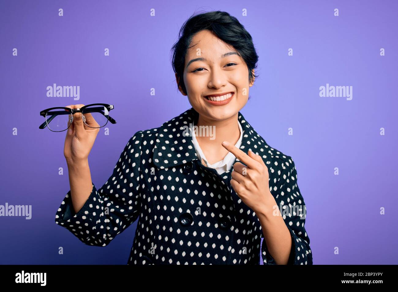 Young beautiful asian optical girl holding vision glasses over isolated ...