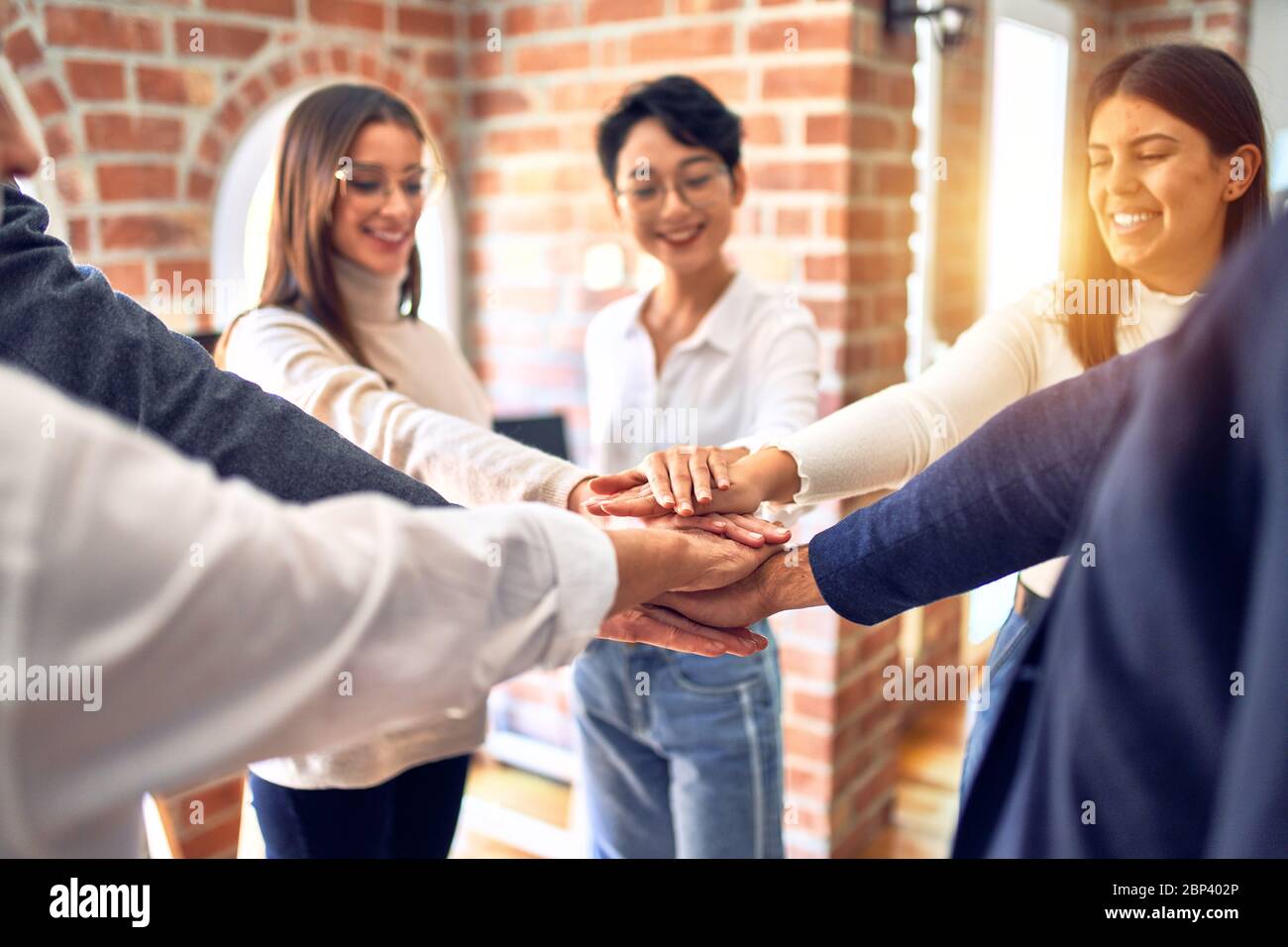 Group of business workers standing with hands together at the office ...