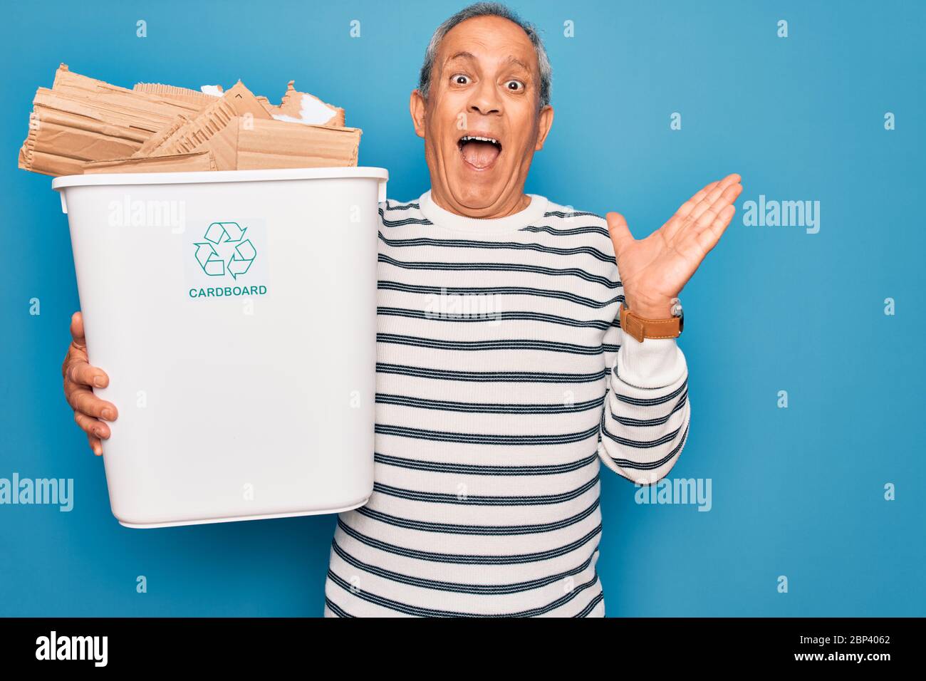 Senior man recycling holding trash can with cardboard to recycle over ...