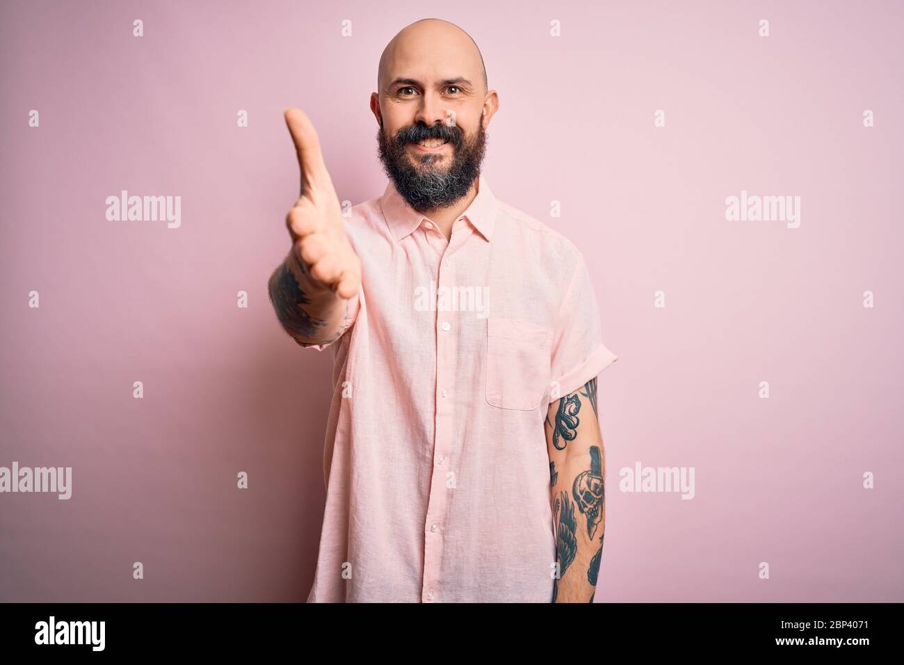 Handsome bald man with beard and tattoo wearing casual shirt over ...