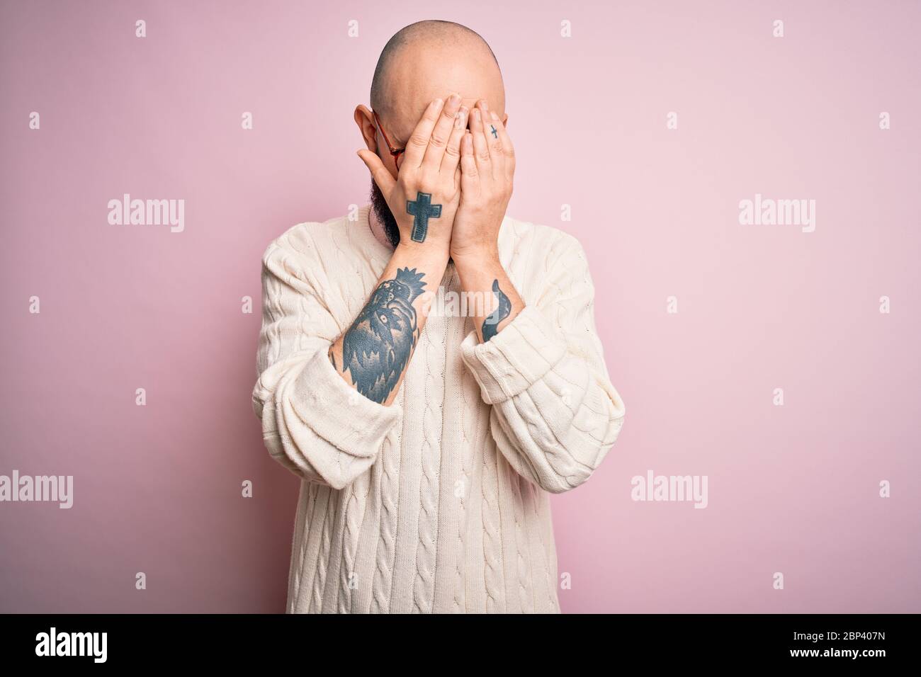 Handsome bald man with beard and tattoo wearing glasses and sweater ...