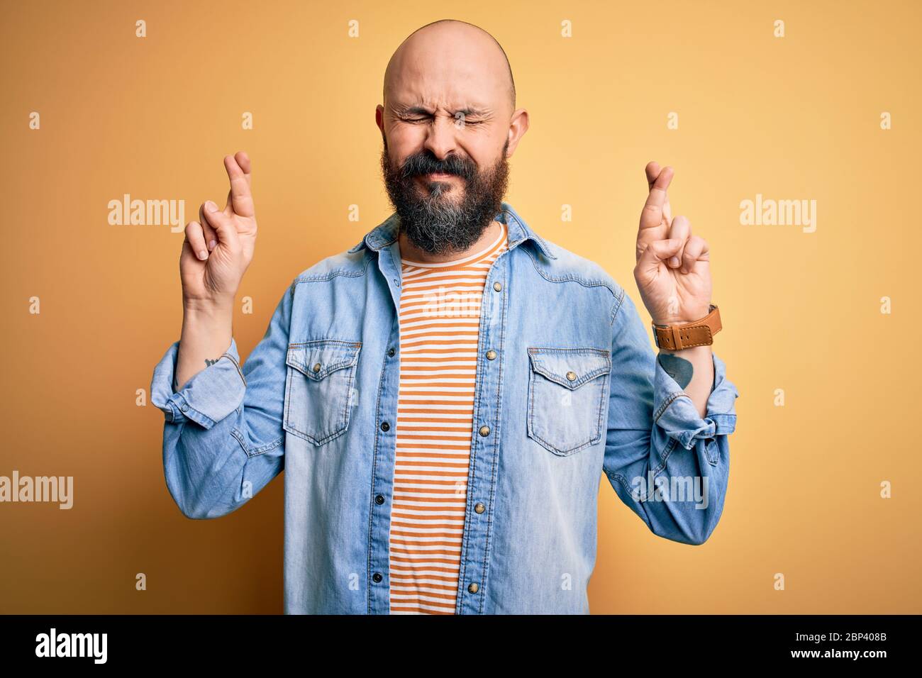 Handsome bald man with beard wearing casual denim jacket and striped t ...