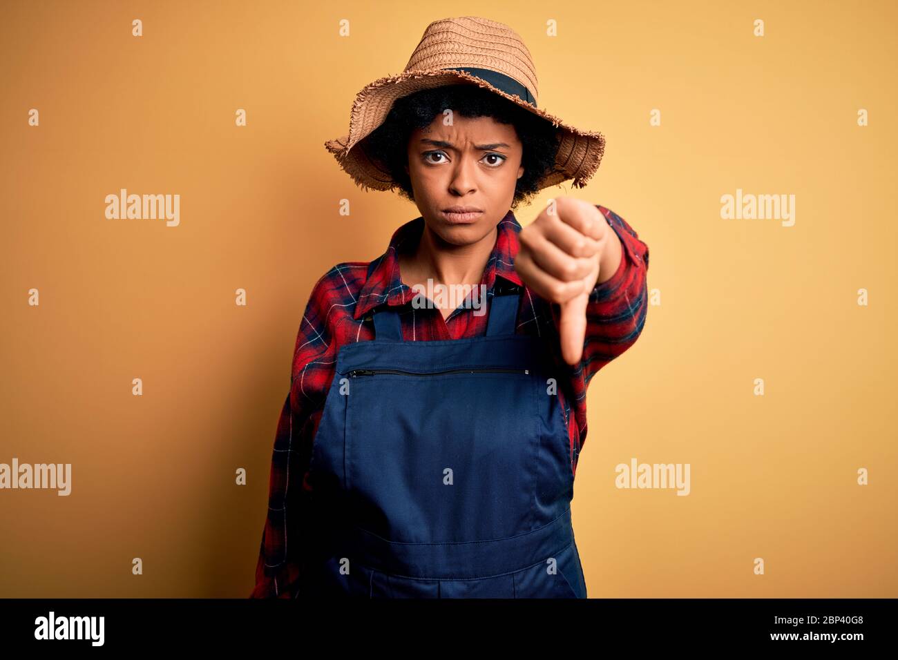 Young African American afro farmer woman with curly hair wearing apron ...