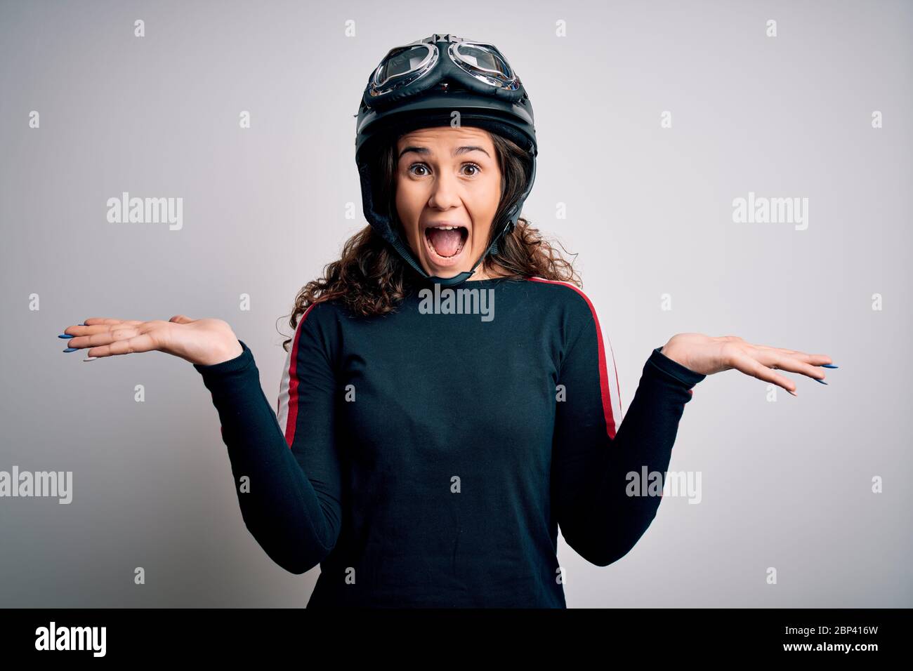 Beautiful motorcyclist woman with curly hair wearing moto helmet over ...
