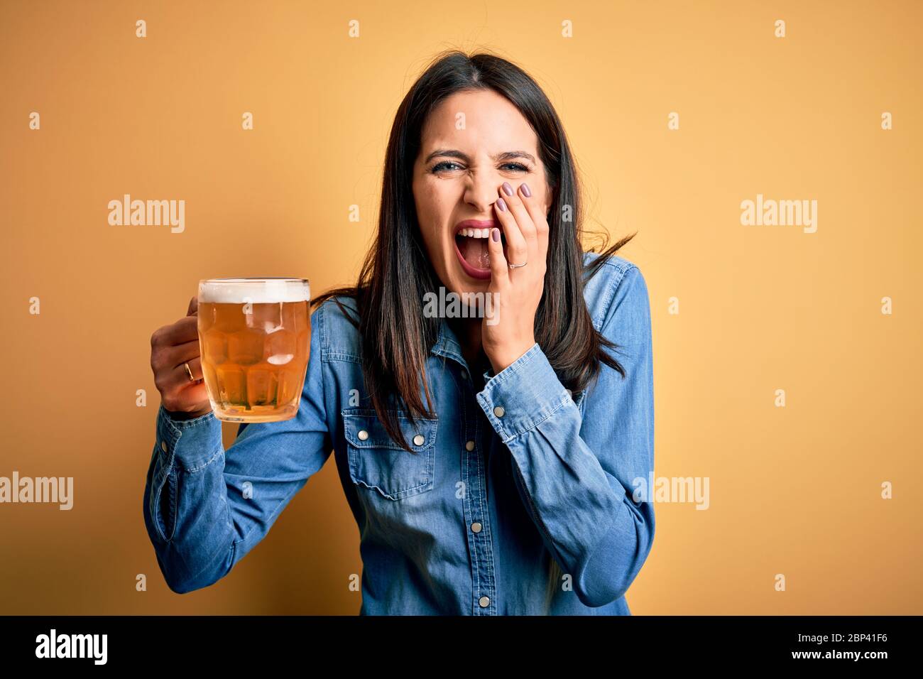 Young woman with blue eyes drinking jar of beer standing over isolated ...