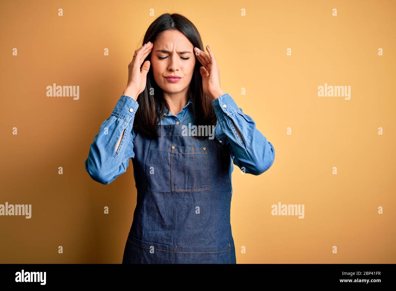 Young baker woman with blue eyes wearing apron standing over isolated ...